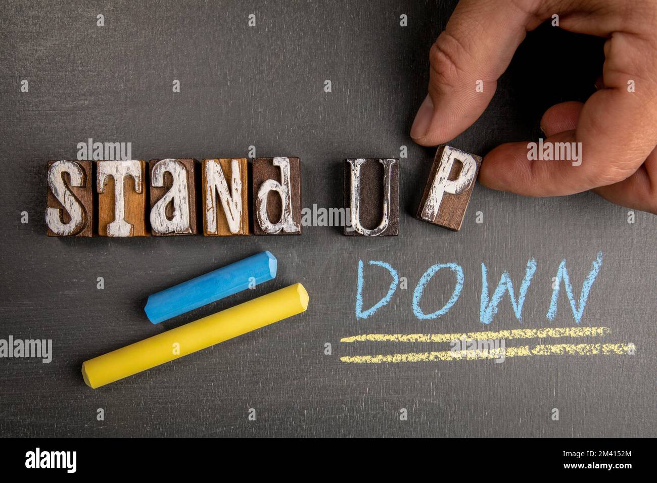 Stand Up and Stand Down. Wooden letter blocks on a dark chalkboard ...