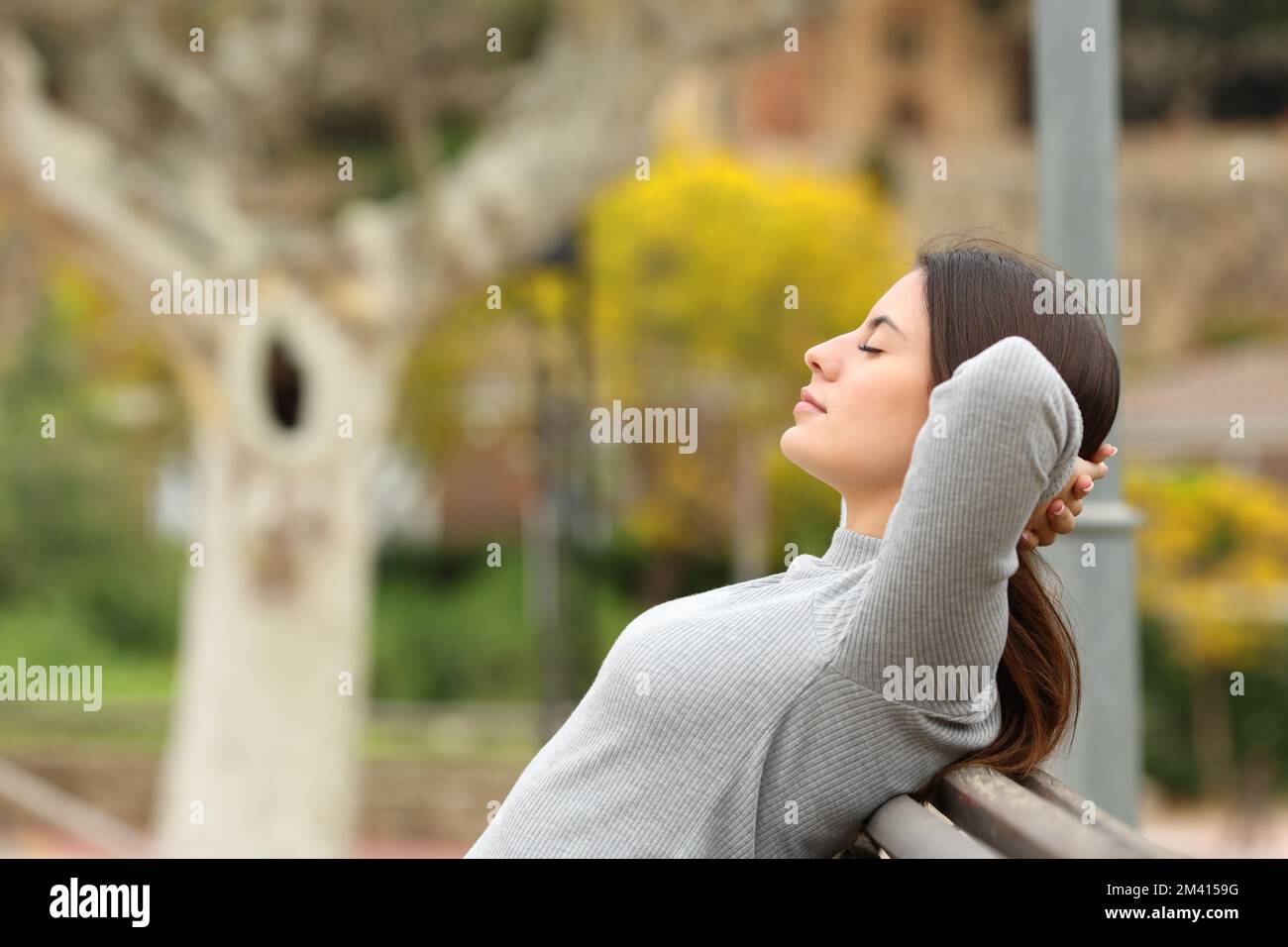 Side view portrait of a woman relaxing in a bench Stock Photo - Alamy