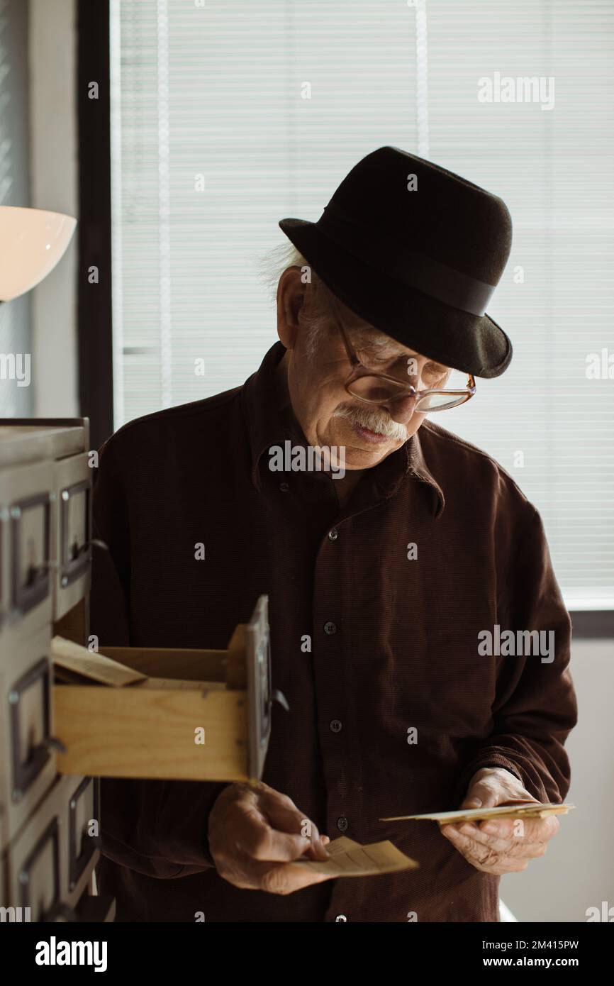 Senior male archivist searching for catalogs Stock Photo - Alamy