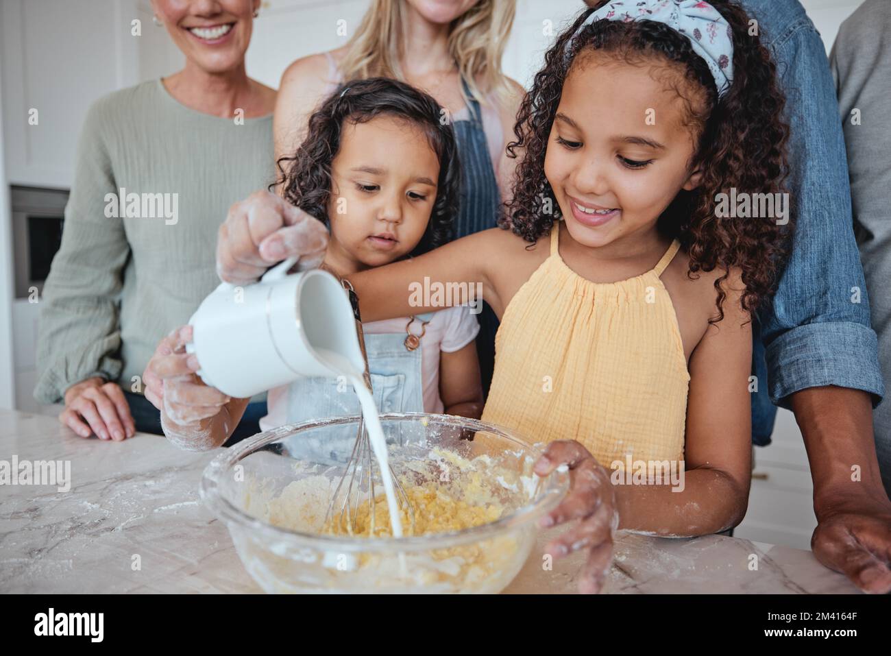 Family, learning and kids pouring milk in bowl while baking in home ...