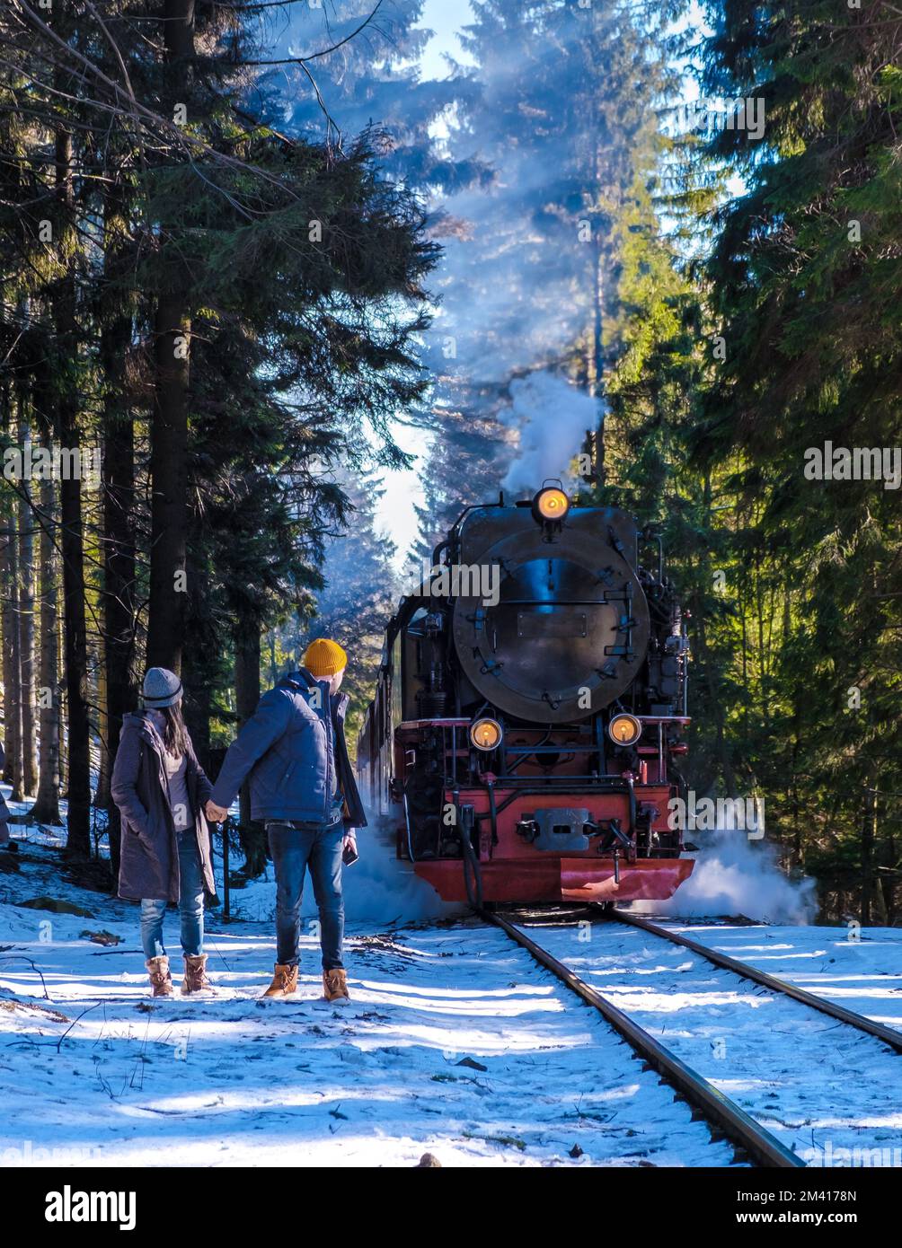 a couple of men and women walking in front of a steam train during ...