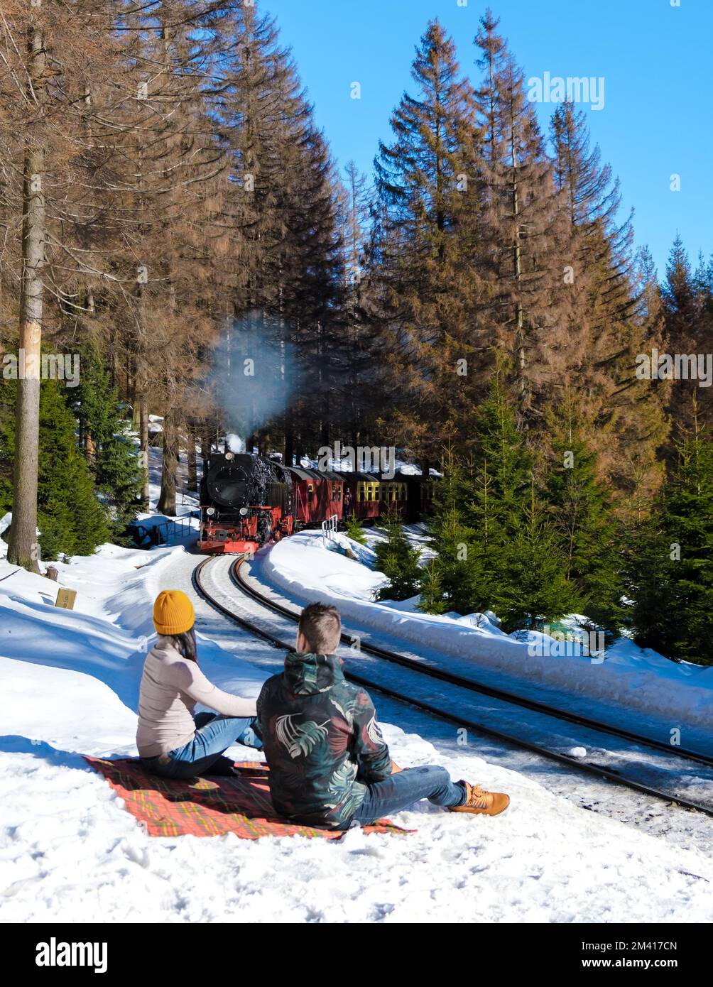 a couple of men and women watching the steam train during winter in the ...