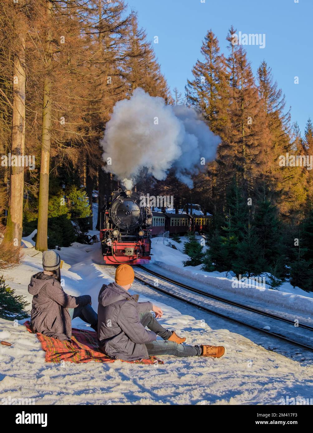 a couple of caucasian men and Asian women watching the steam train ...
