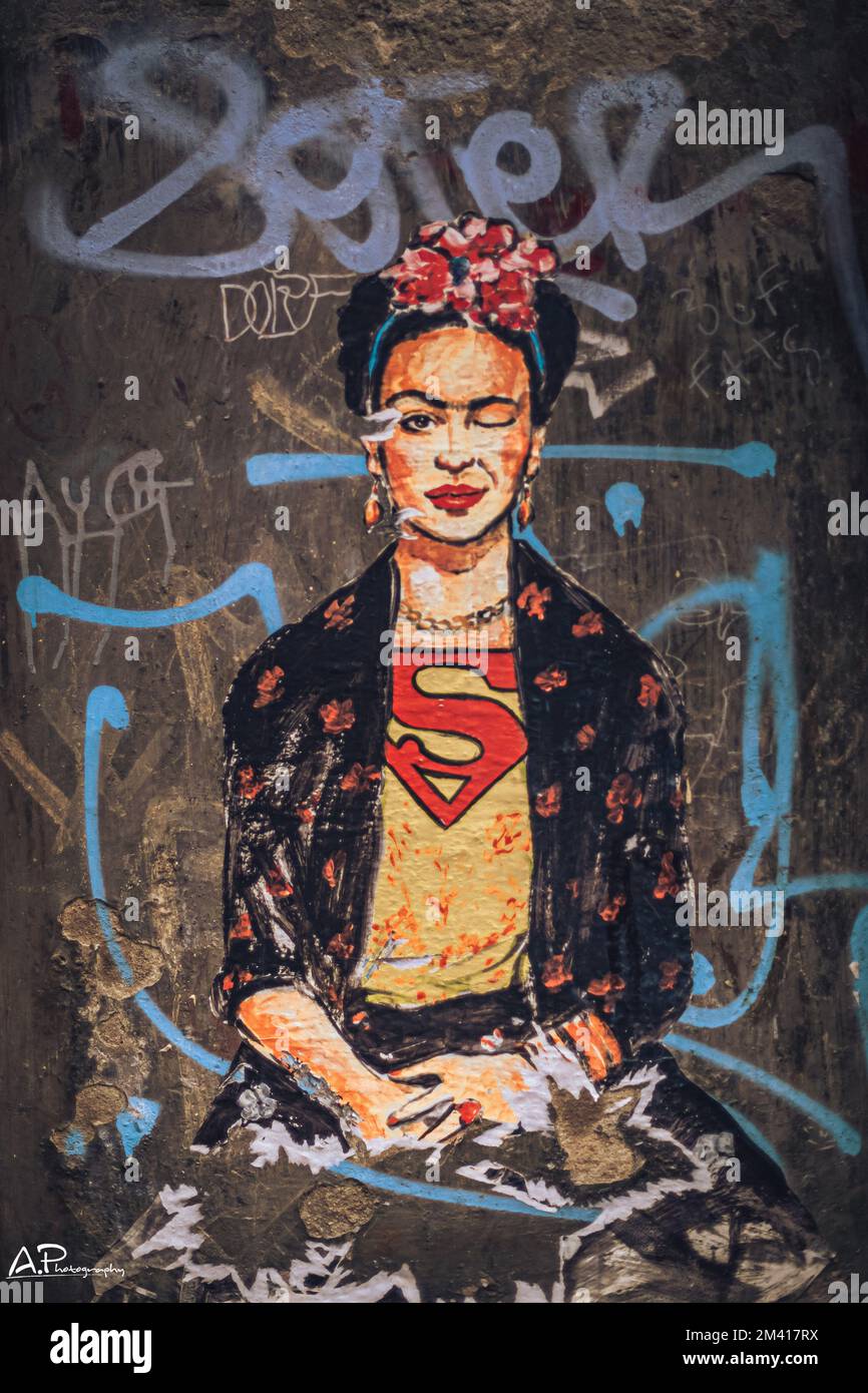 A vertical shot of Frida Kahlo portrait with superman shirt on a wall ...