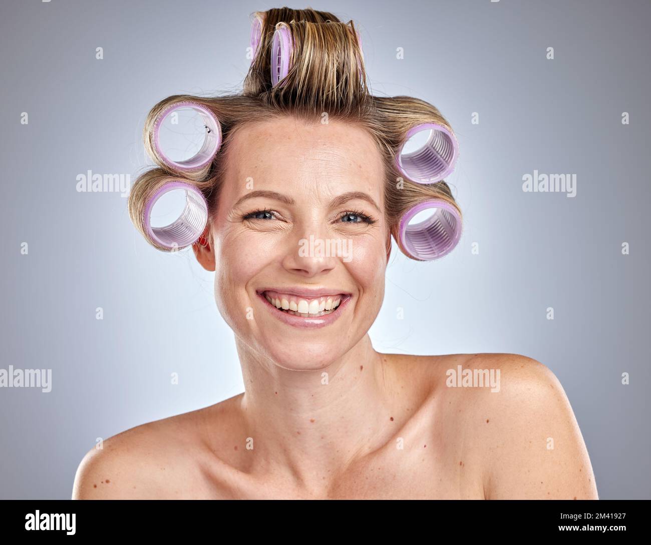 Face, hair care and woman with hair roller in studio isolated on gray ...