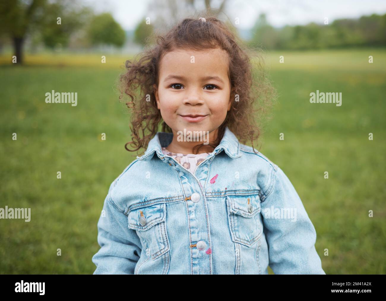 Child, face and park with a smile outdoor on a grass field for freedom ...