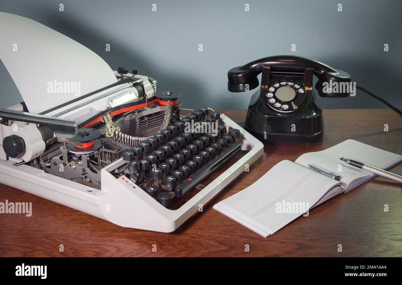 Retro typewriter and old telephone on the table, checkbook, ink pen ...