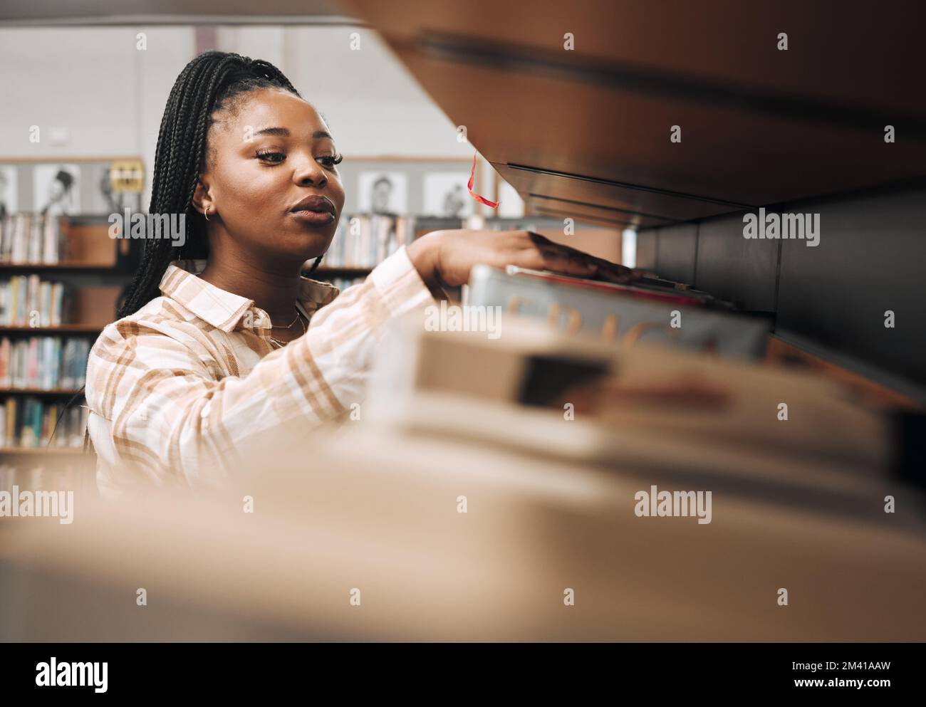 Black woman, library shelf and books for reading, student knowledge or ...