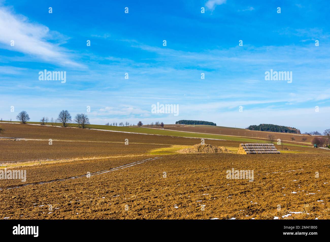 Straw bales and manure on the countryside field. Spring fields and ...