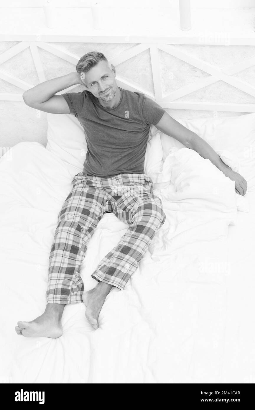 Morning rest and relaxation. Happy guy relax in bed. Pajama man. Waking ...