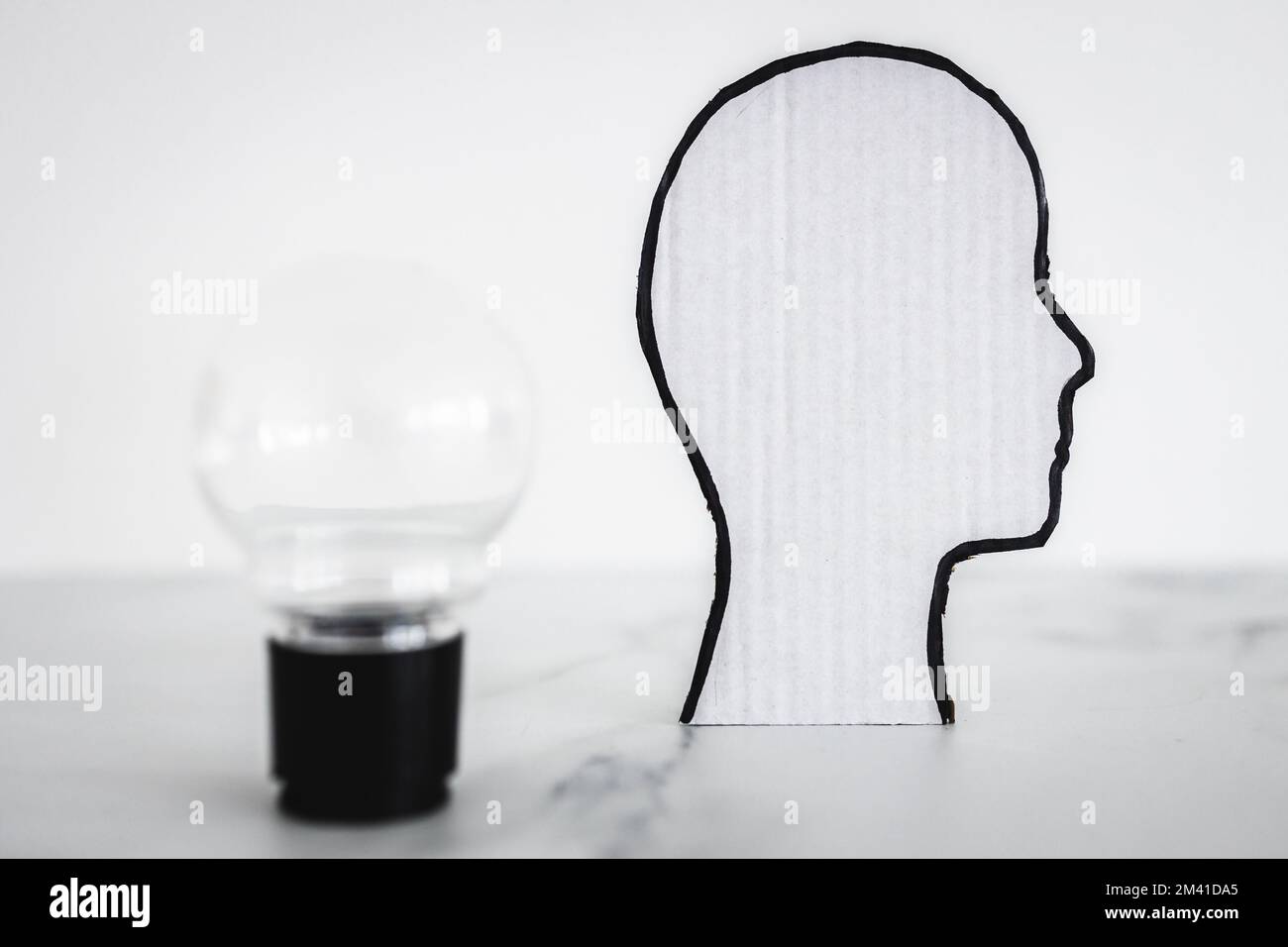 cardboard head with light bulb on white marble background, psychology ...