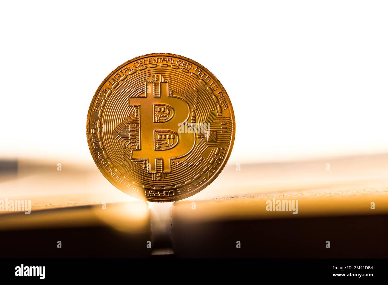 Gold bitcoin coin placed on white background in the light of sunset ...