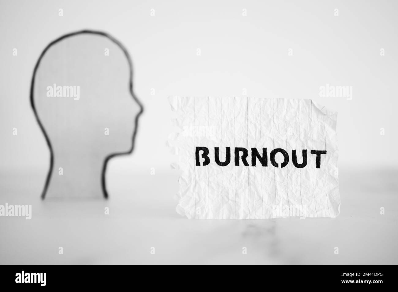 cardboard head next to Burnout text on white marble background ...