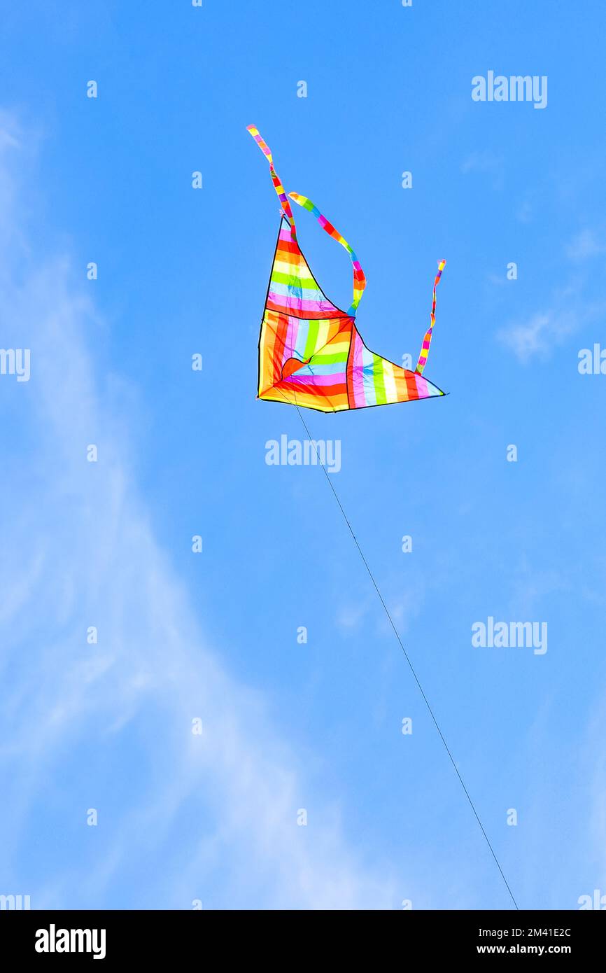 big rainbow colored kite flying high in the blue sky with some white ...