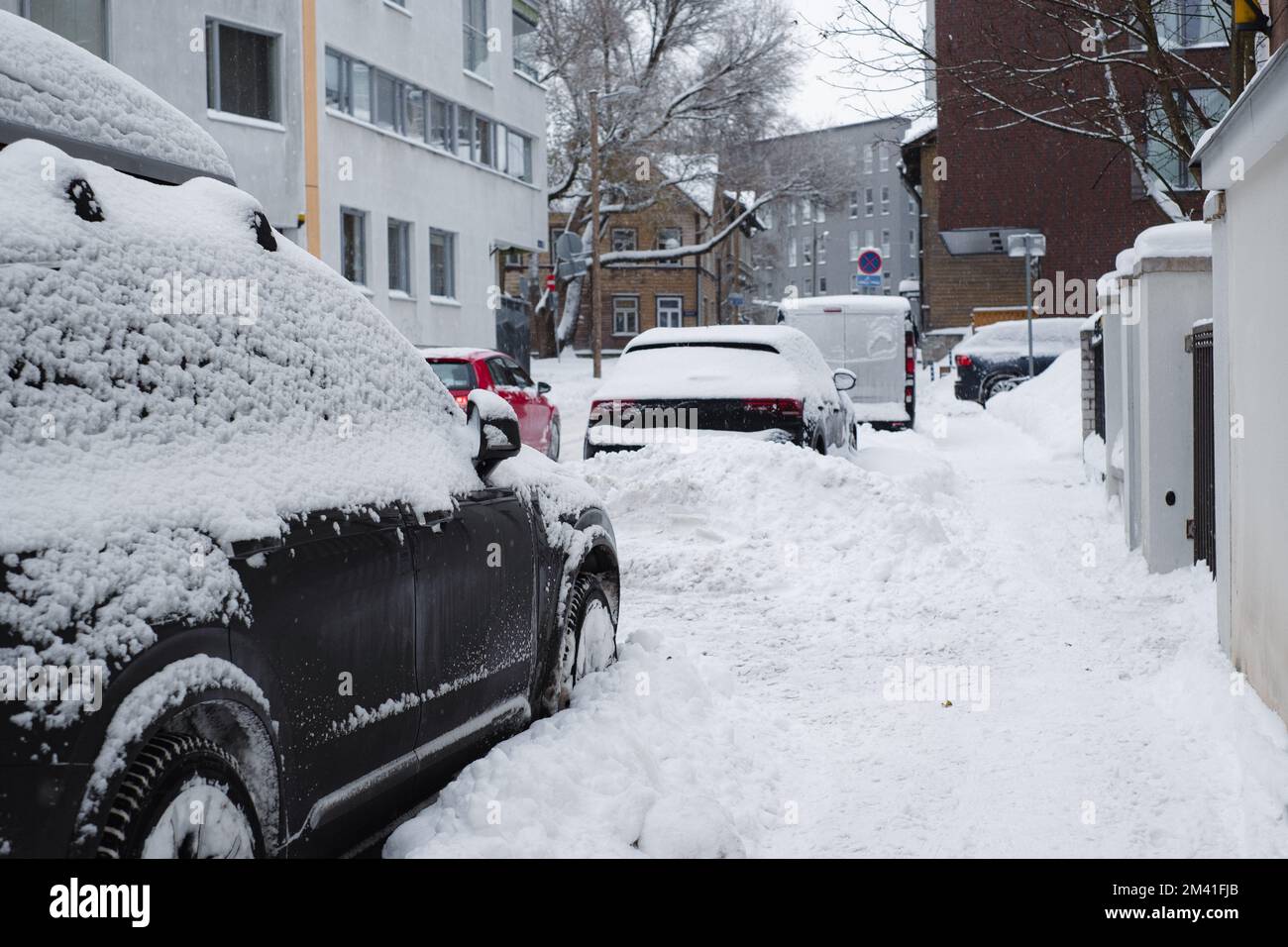 Difficult weather conditions. Street and sidewalk under snow piles ...