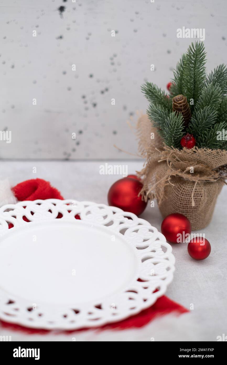 a plate on a santa hat a small Christmas tree on a concrete background ...
