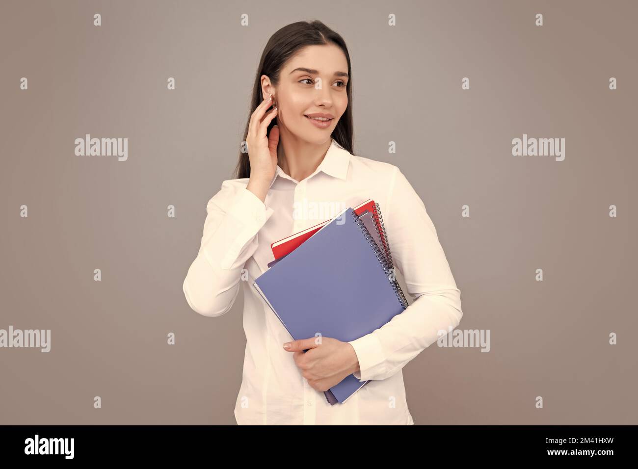 Smiling young woman college student holding book on isolated gray ...