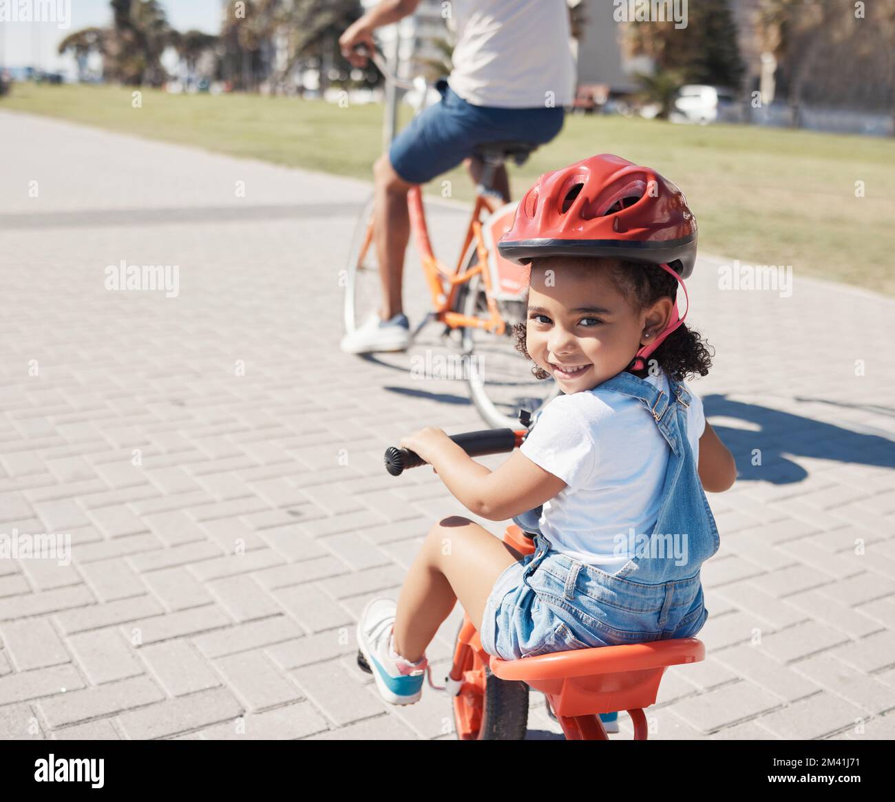 Happy, portrait or child cycling on bike learning to ride outdoors for ...