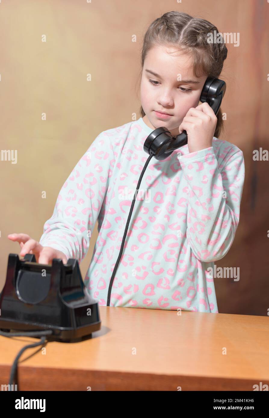 Portrait of a teenage girl. The girl dials a number on an old telephone ...