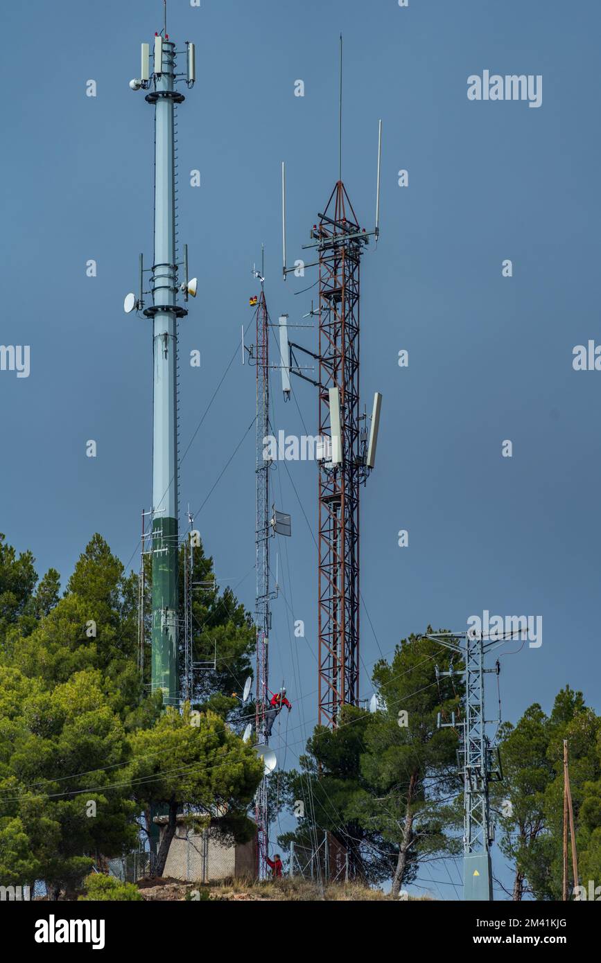 Unrecognizable workers fixing communication antenna with protection ...