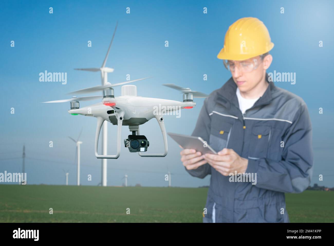 Engineer with tablet computer controls drone on a background of wind ...