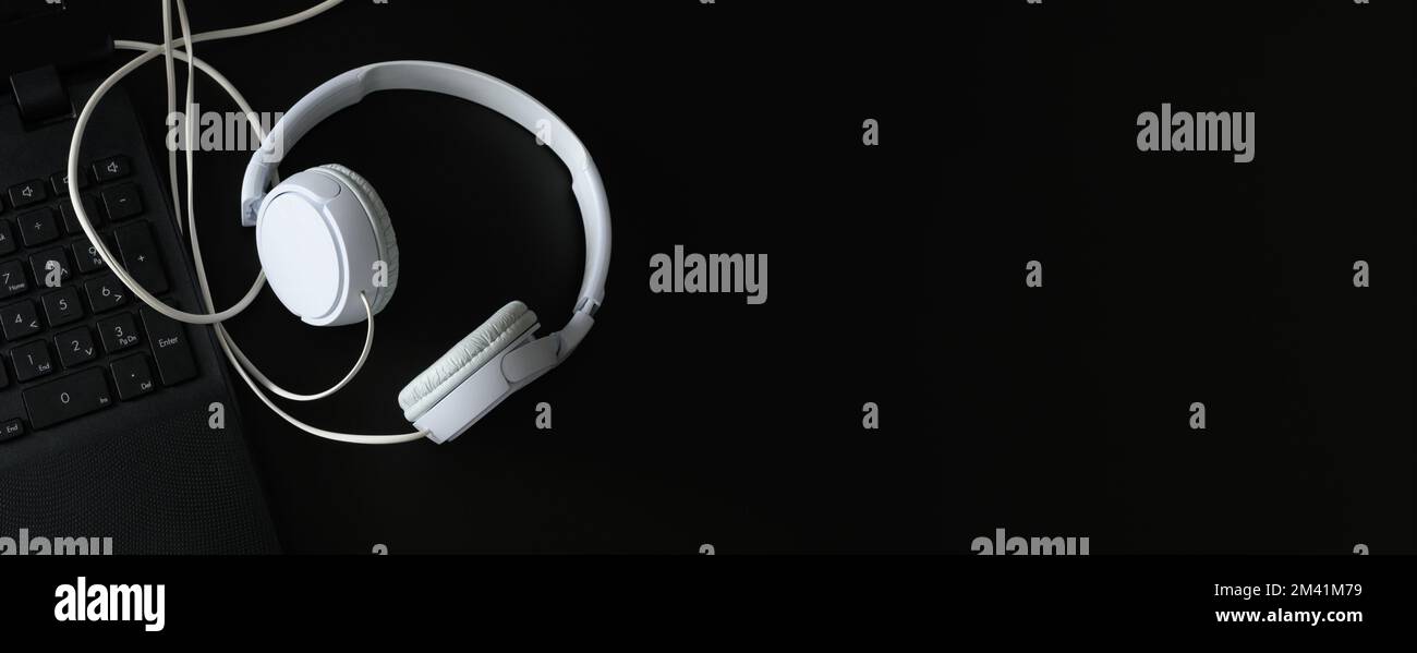 White headphones and part of notebook on a black background. Horizontal ...