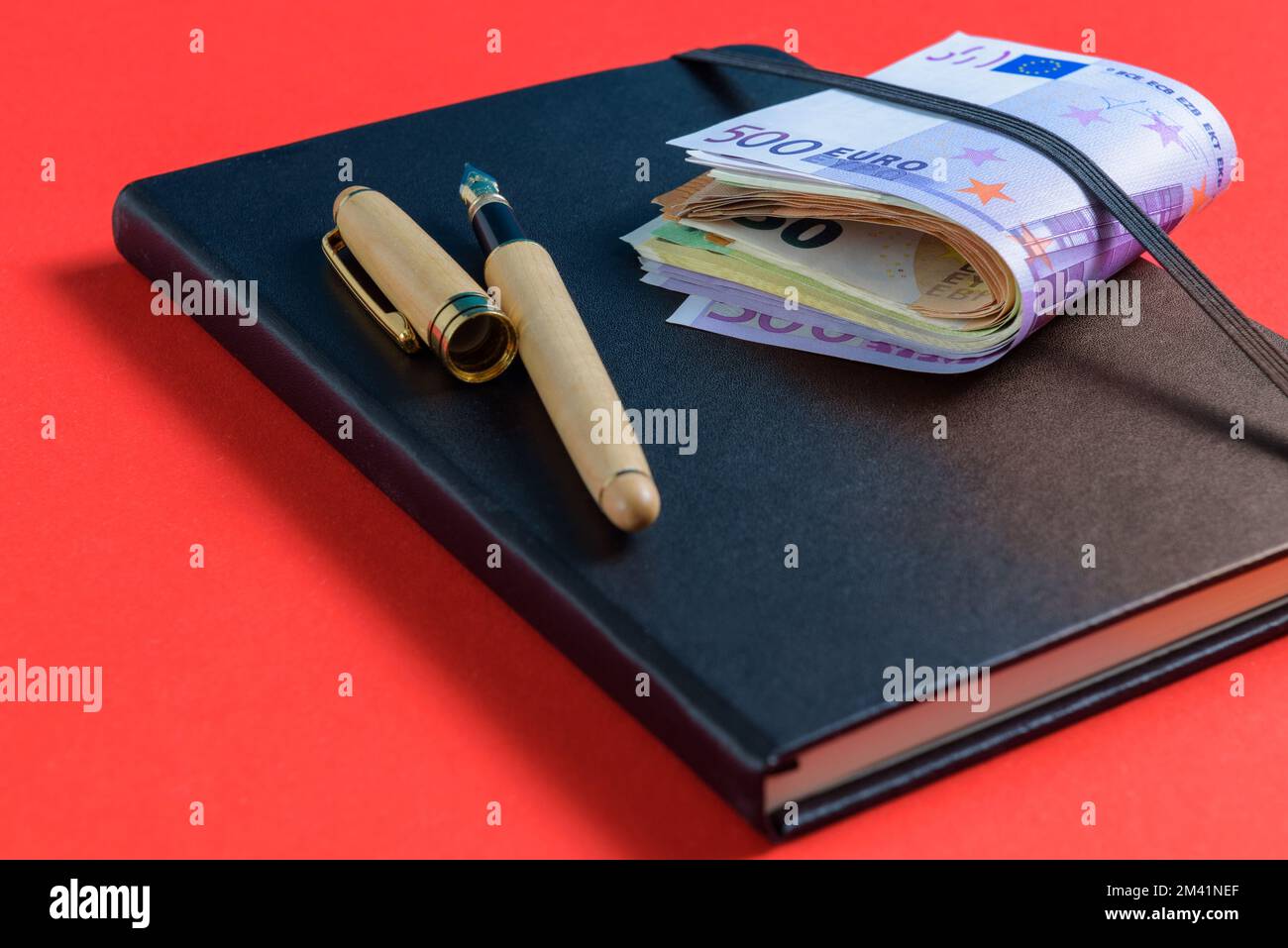 Accounting black book, euro banknotes and pen on red background Stock ...