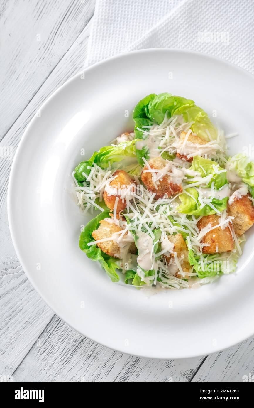 Portion of Caesar salad in the white plate Stock Photo - Alamy