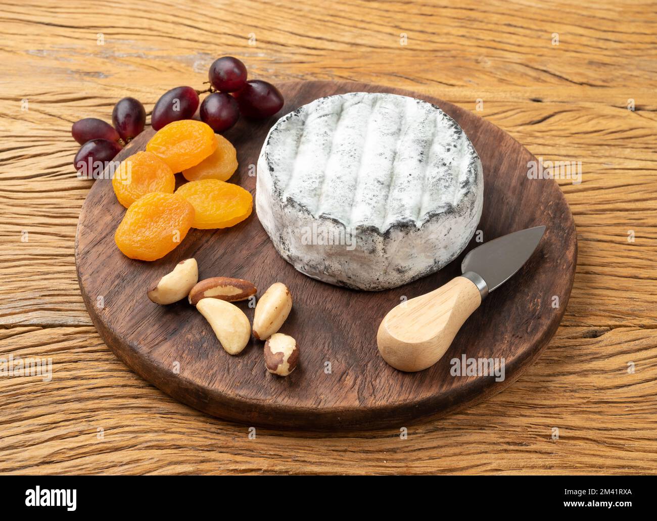 Brazilian artisan Lua Cheia cheese with fruits and nuts over wooden ...