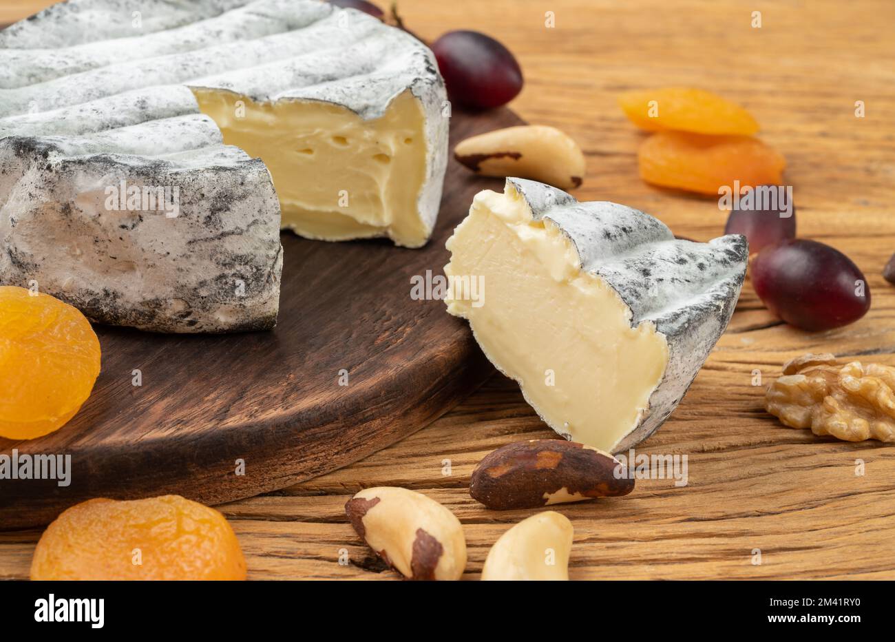 Brazilian artisan Lua Cheia cheese with fruits and nuts over wooden ...