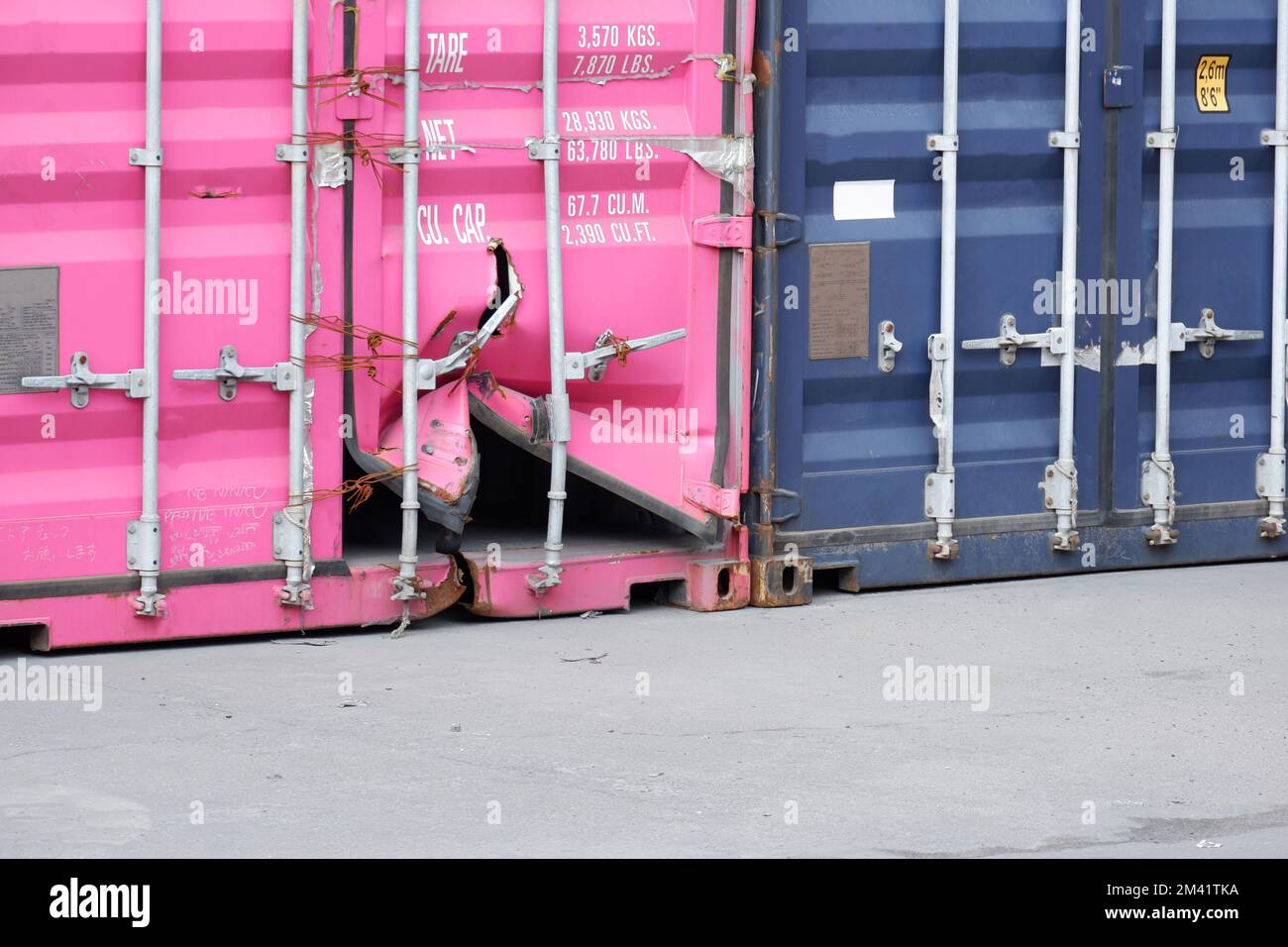 Shipping containers are stacked at the port. one of them is damaged ...