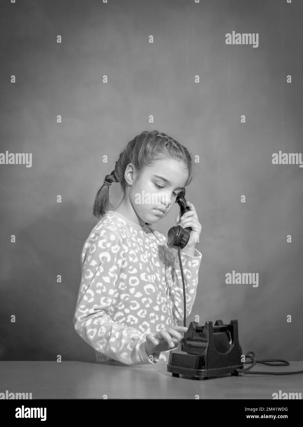 Retro portrait of a teenage girl. The girl dials a number on an old ...