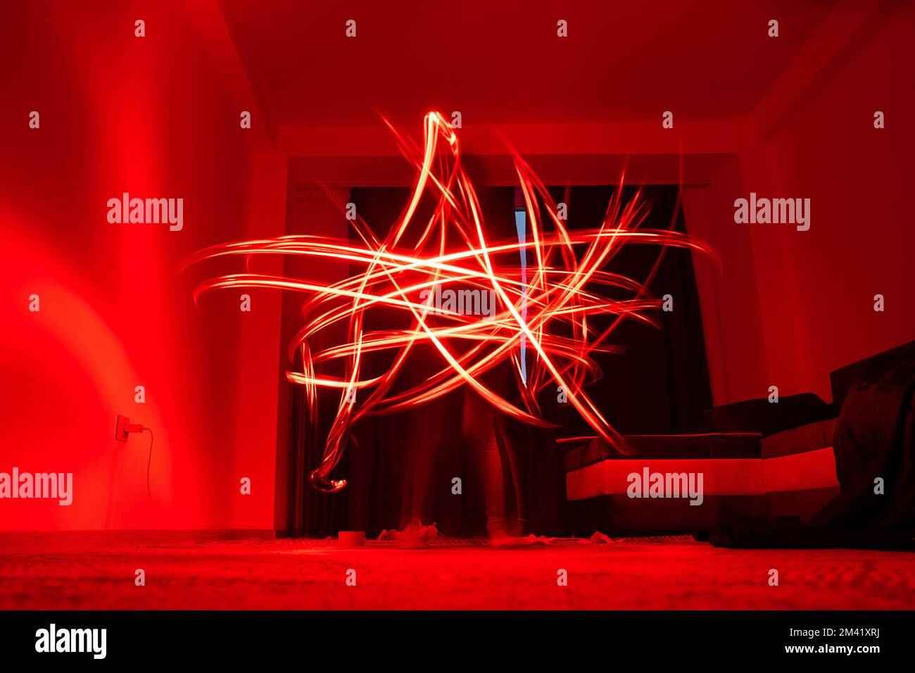 Red light traces in a star shape from long exposure shot. In a dim room ...