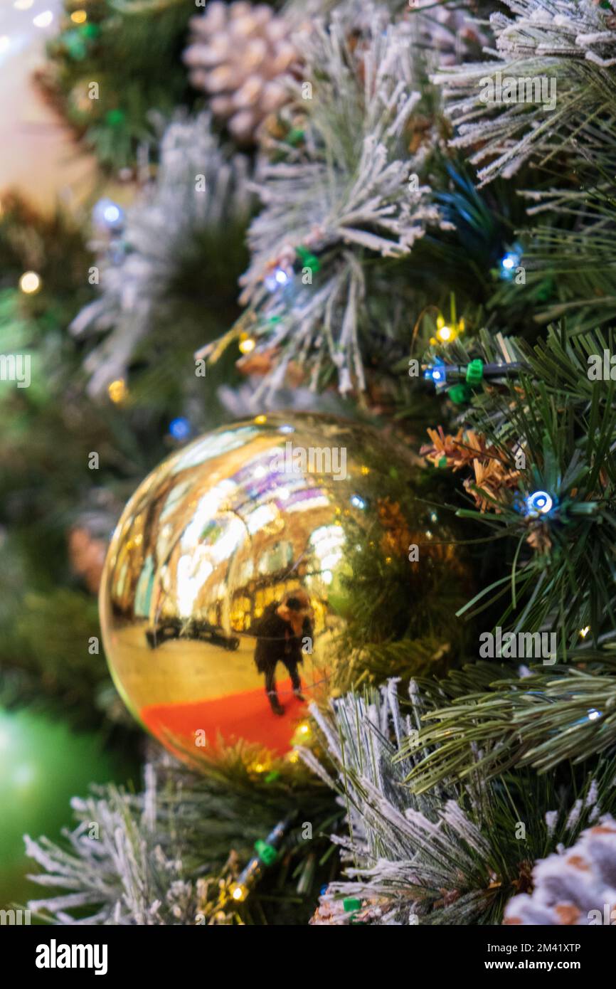 Glittery golden ball ornament hangs from bough of a Christmas tree ...