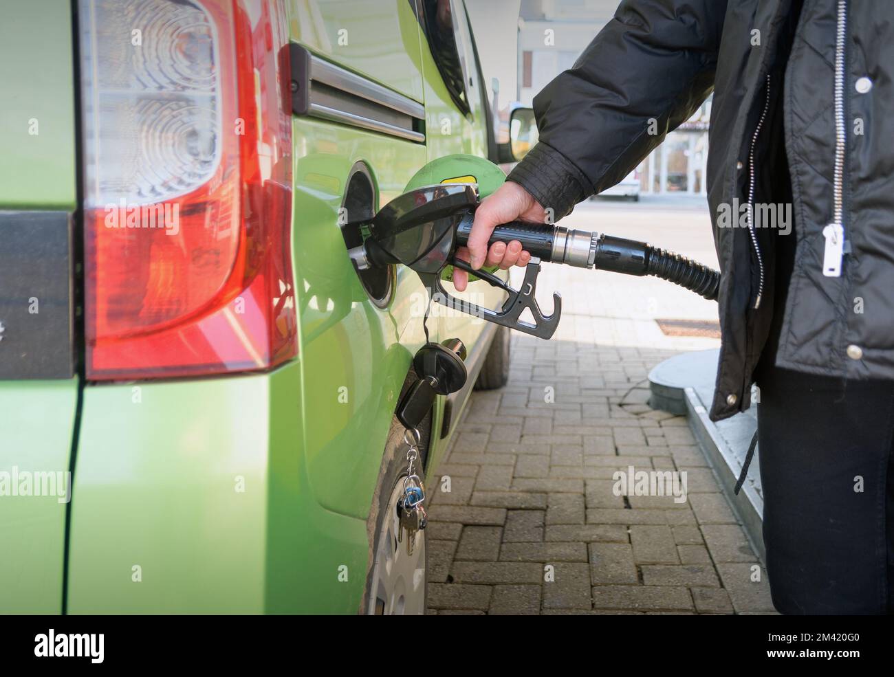 Woman refilling petrol in gas station at green car Stock Photo - Alamy