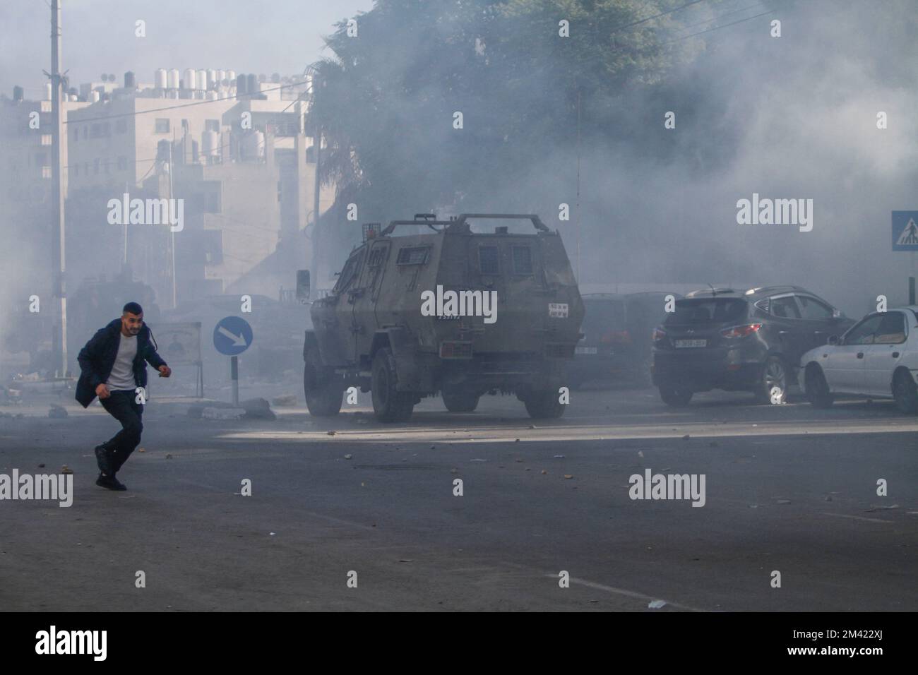 A Palestinian flees to hide from tear gas fired by the Israeli army at ...