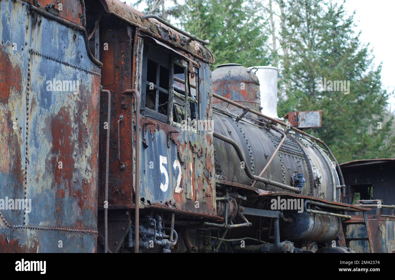 A rusty antique locomotive cab with tall green trees in the background Stock Photo - Alamy