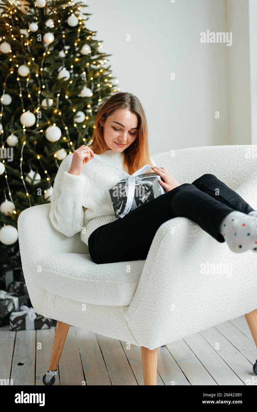Smiling young female enjoy New Year winter holiday at home, dreaming or ...