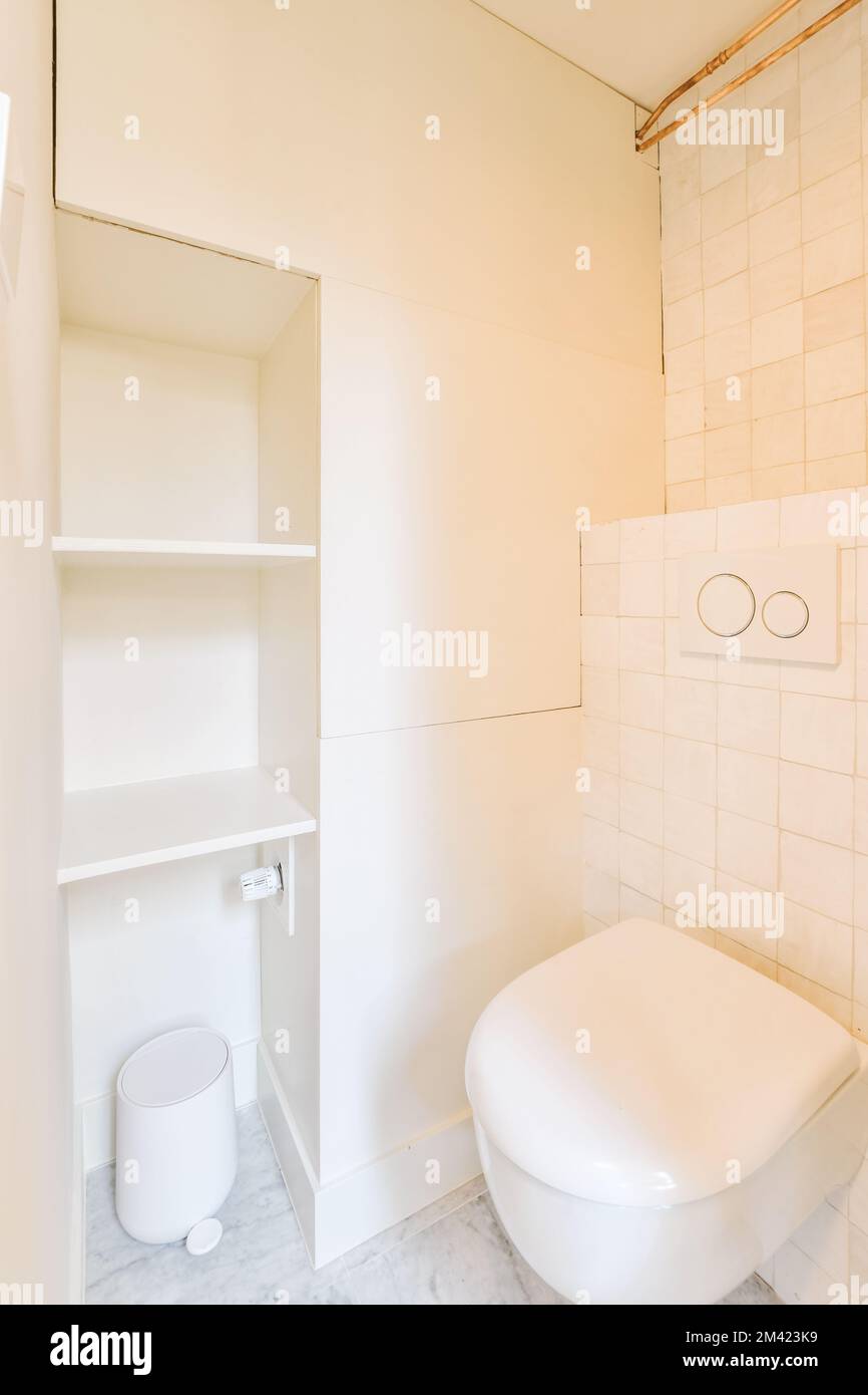 a white toilet in a bathroom with shelves on the wall and an open door ...