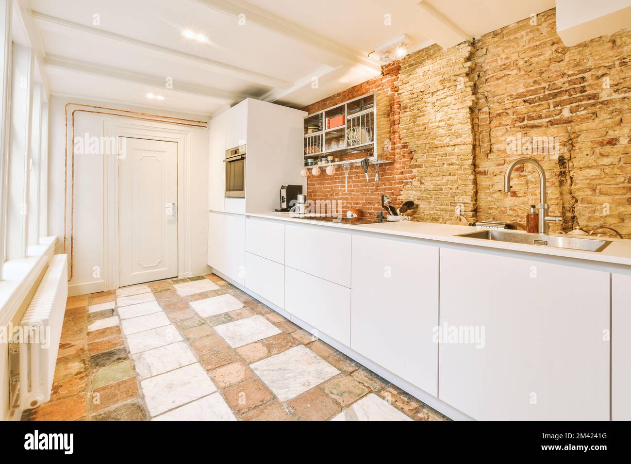 a kitchen area with brick walls and white cupboards on either side ...
