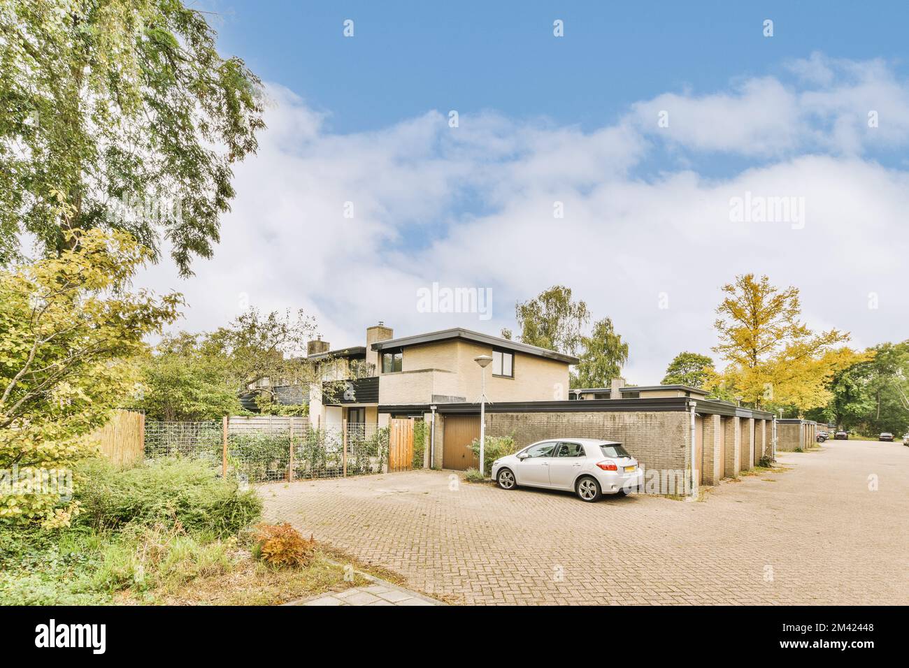 a car parked in front of a house with trees and bushes around the ...