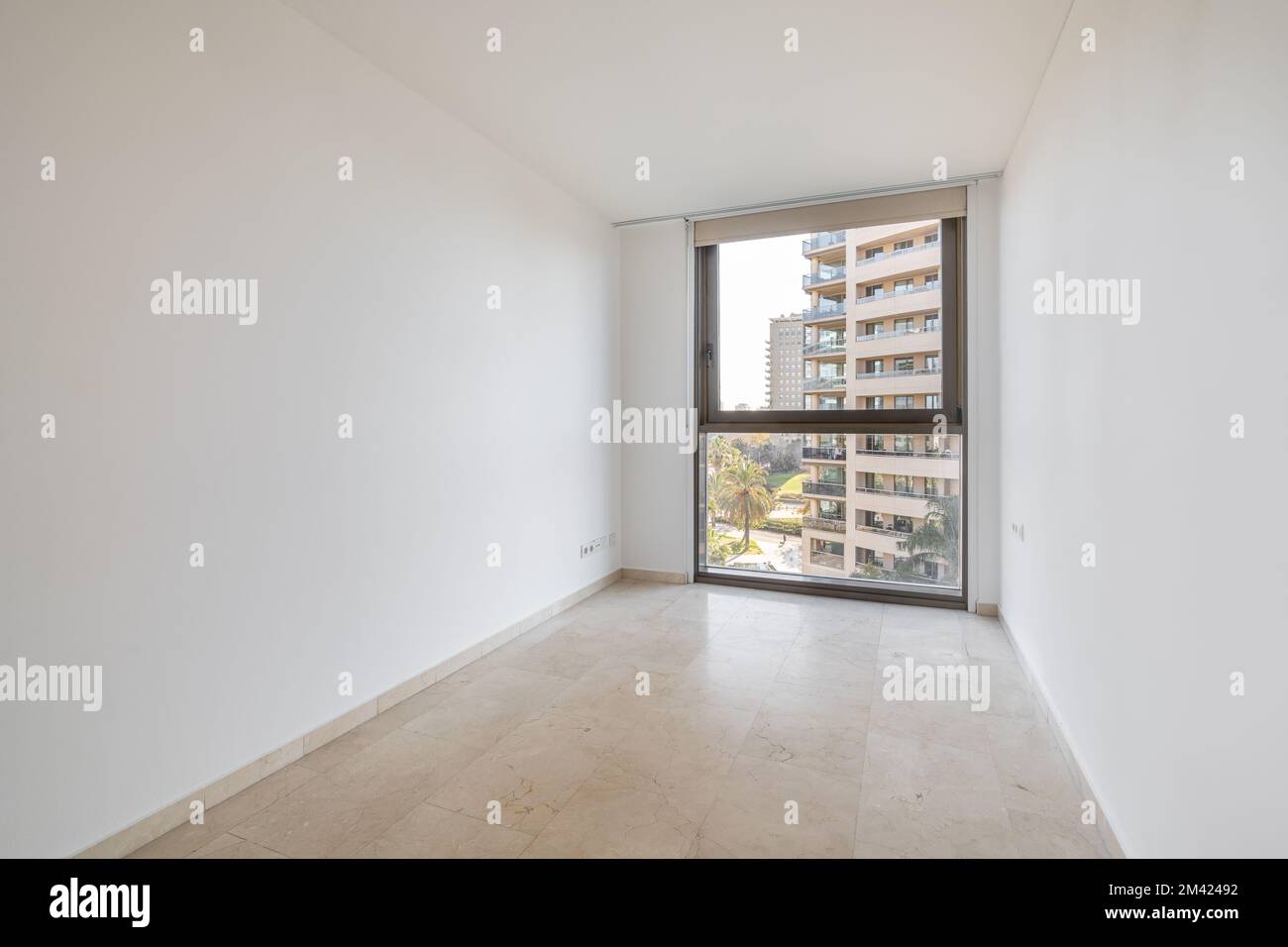 An empty spacious white square room with a large floor-to-ceiling brown ...