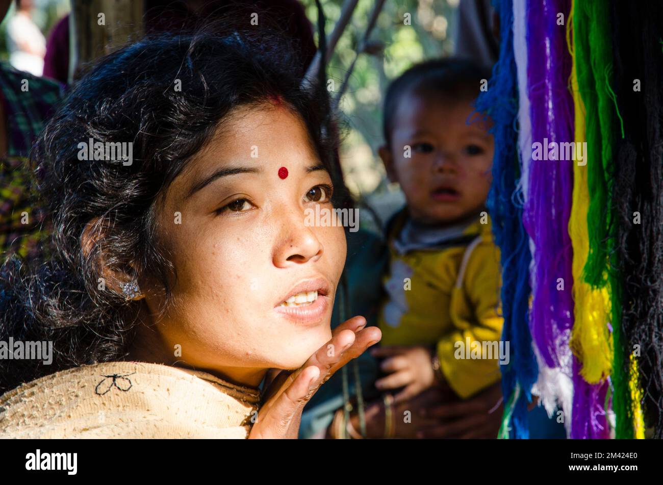 Young lady of the Mishing tribe weaving at a handloom in front of her ...