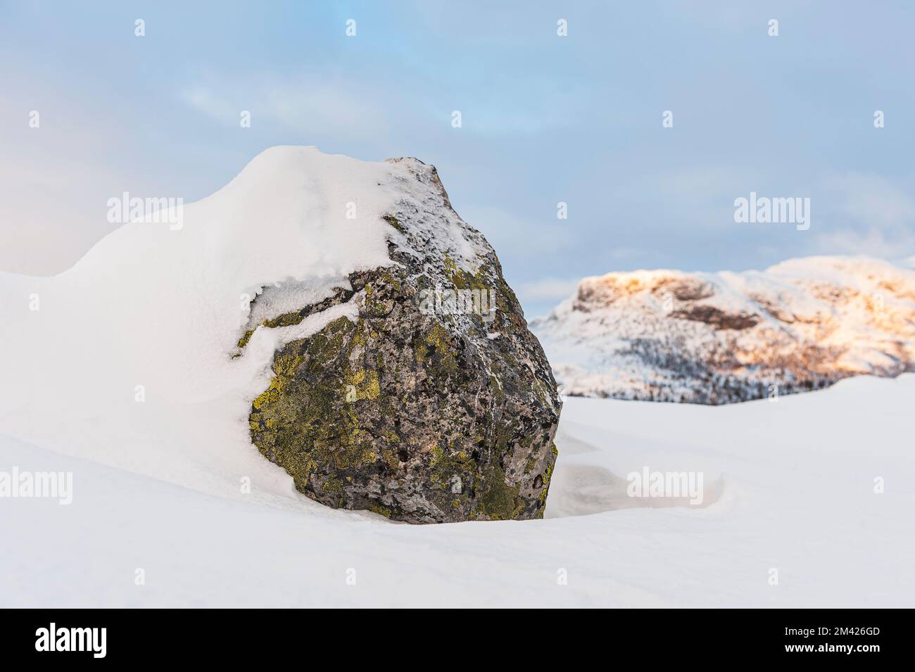 Boulder in front of winter mountain Stock Photo - Alamy