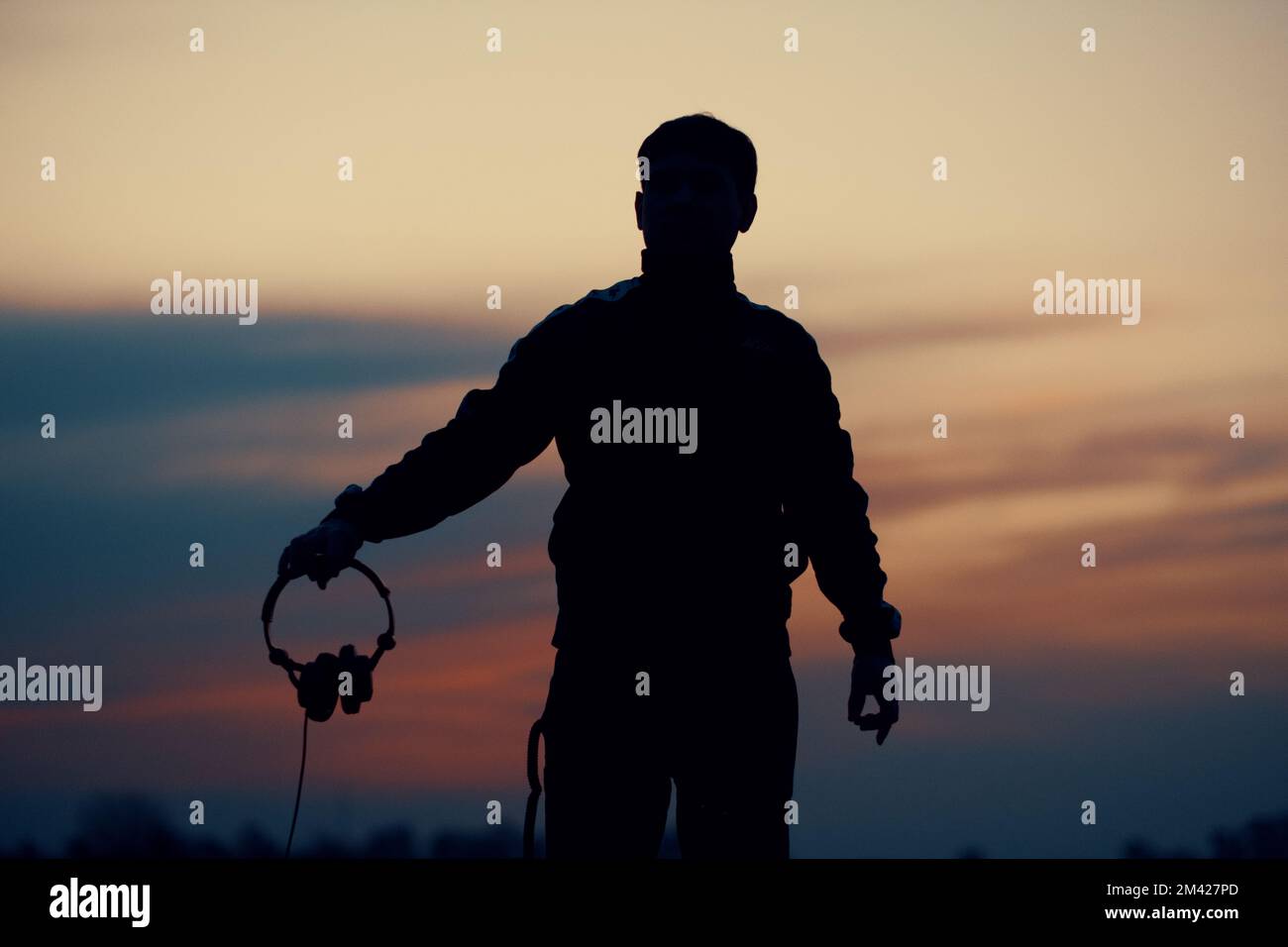 A silhouette of a person holding headphones on the background of a ...