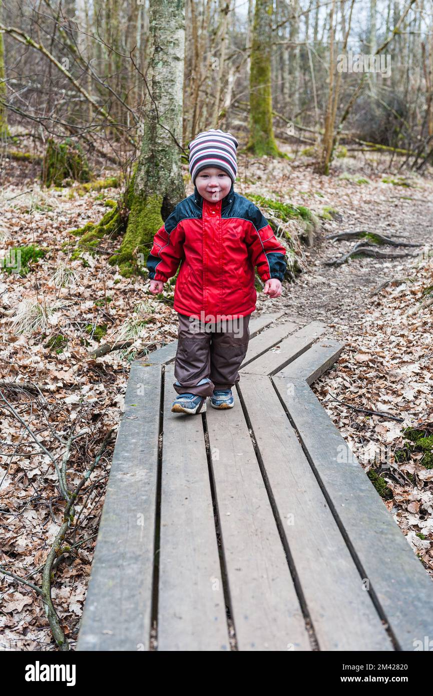 Young boy walking on wooden walkway Stock Photo - Alamy