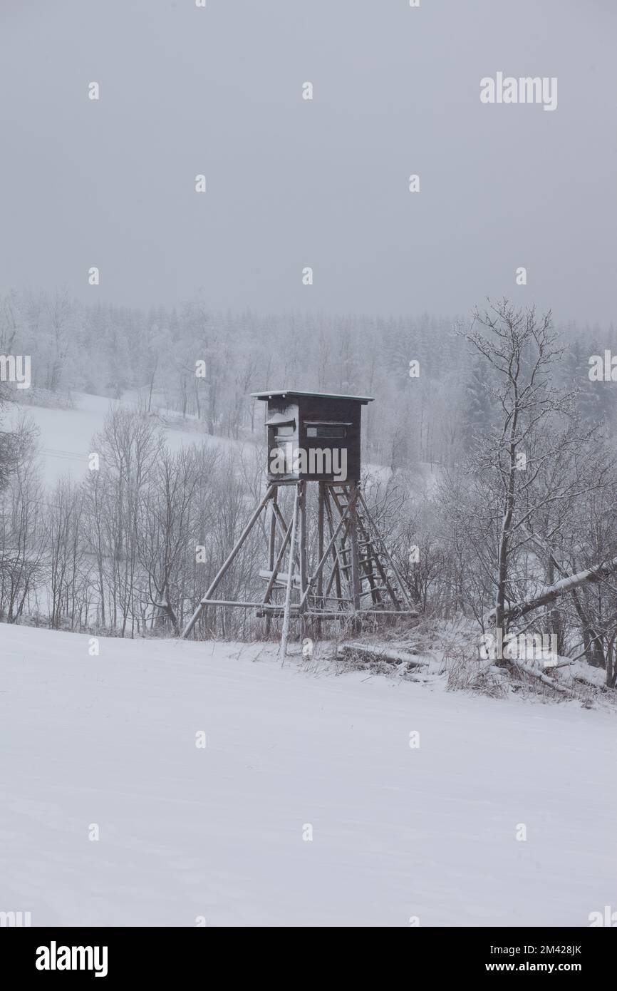 A hunting tower built of wood is positioned near a grove of trees ...