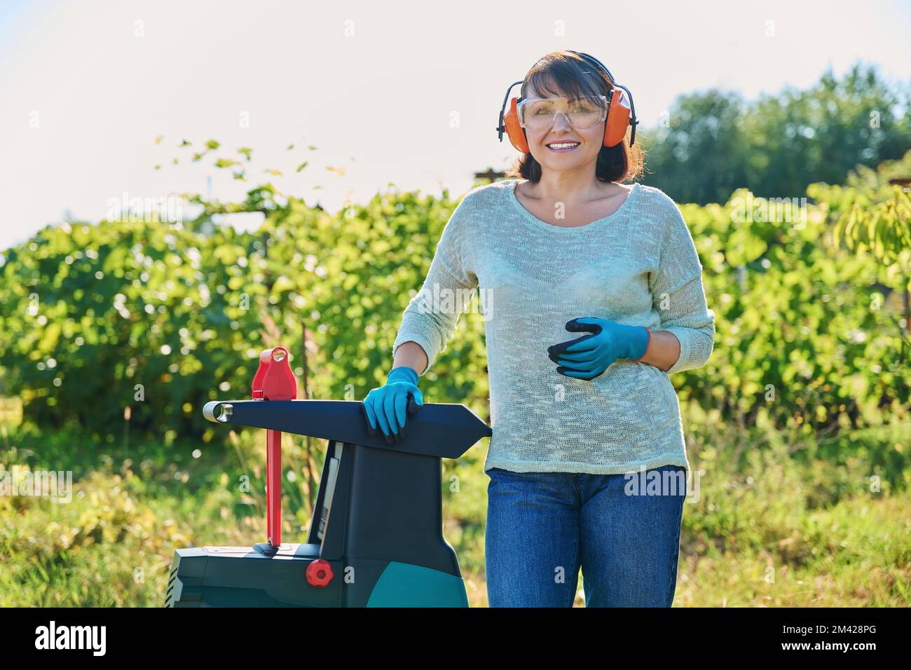 Woman using electric garden shredder for branches and bushes Stock ...