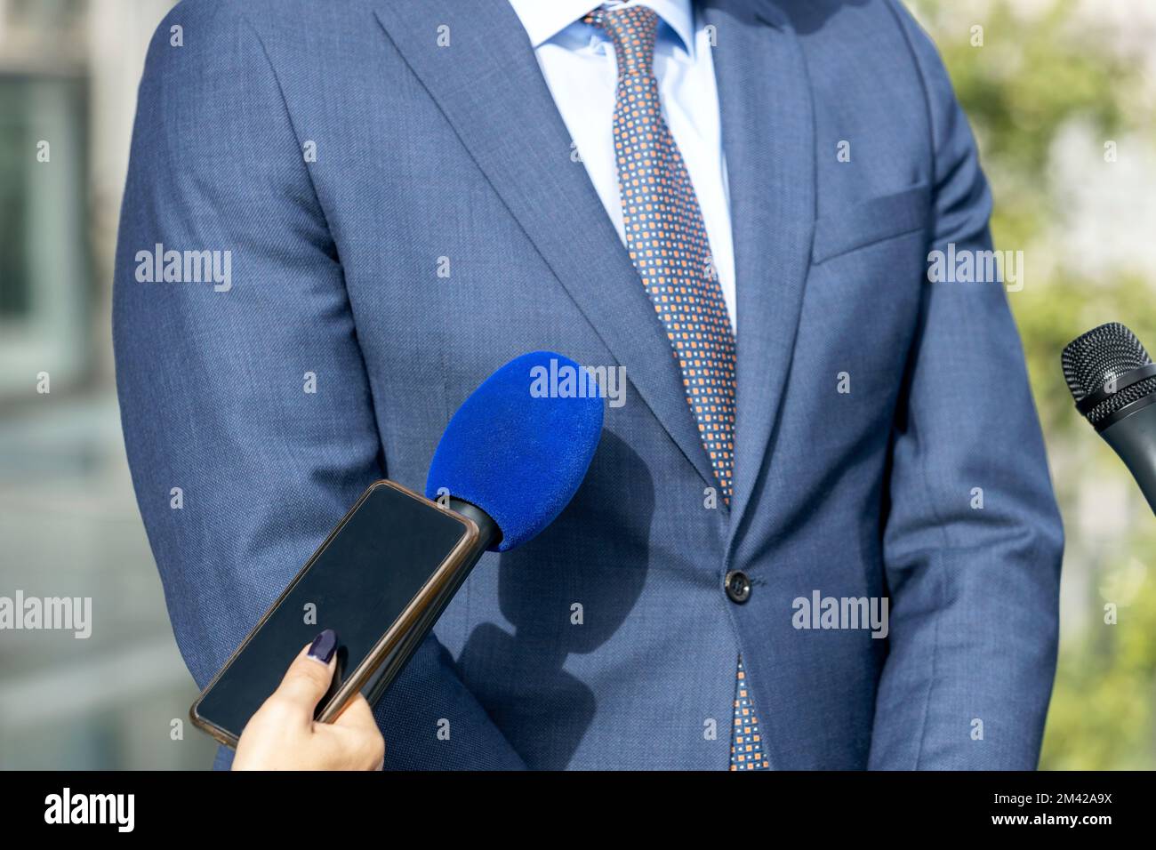 Reporter at news conference holding microphone and smartphone making media interview Stock Photo ...