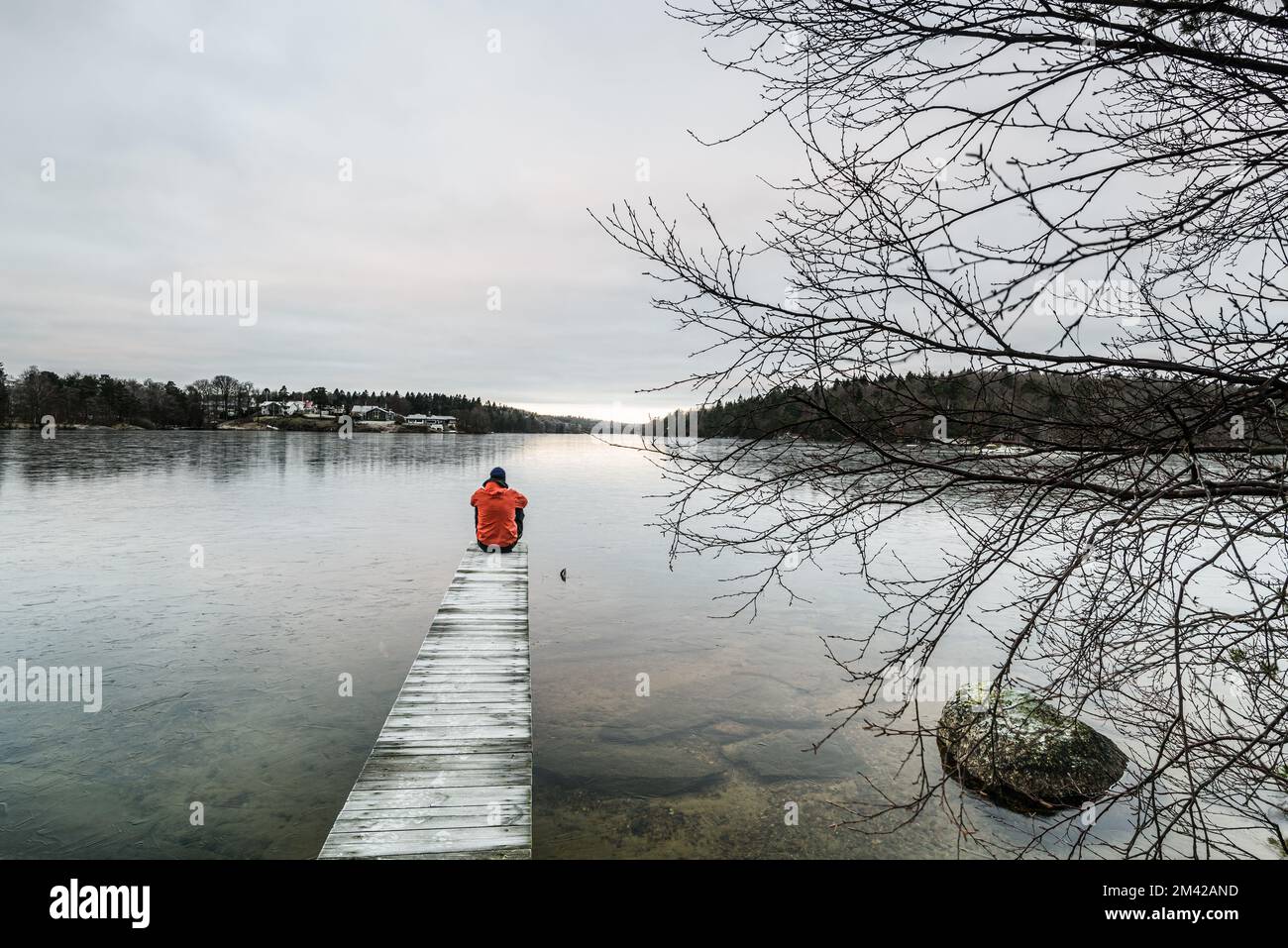 Lonely man sitting on jetty, Sweden Stock Photo - Alamy